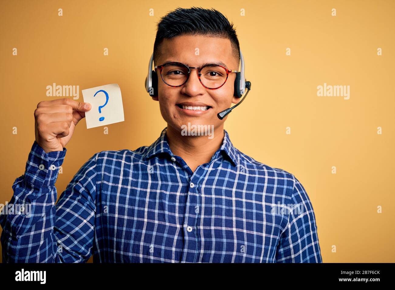 Young latin call center agent man holding question mark reminder paper ...