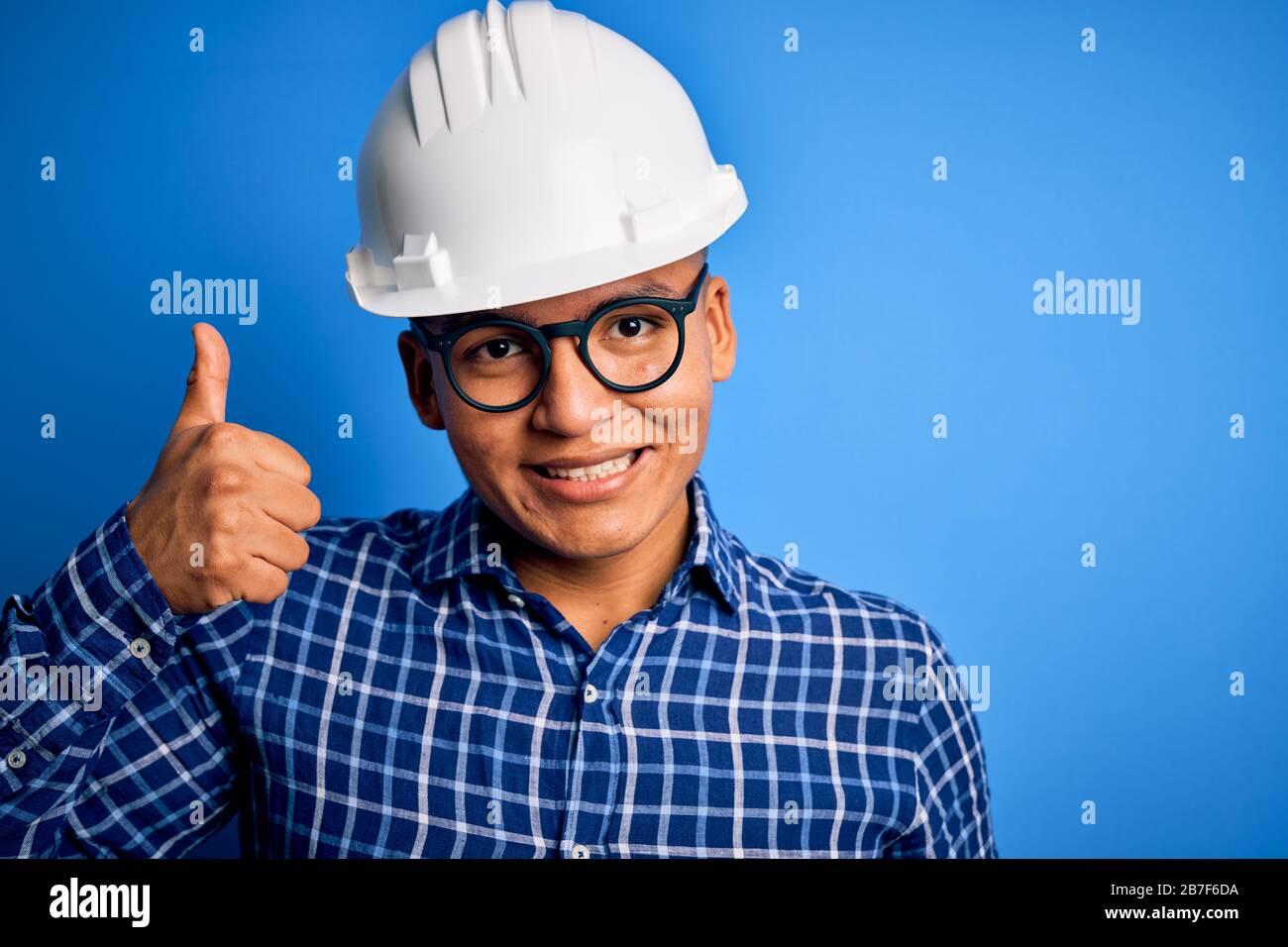 Young handsome engineer latin man wearing safety helmet over isolated ...