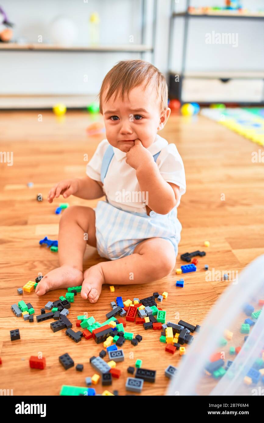 Adorable toddler crying around lots of toys at kindergarten Stock Photo ...