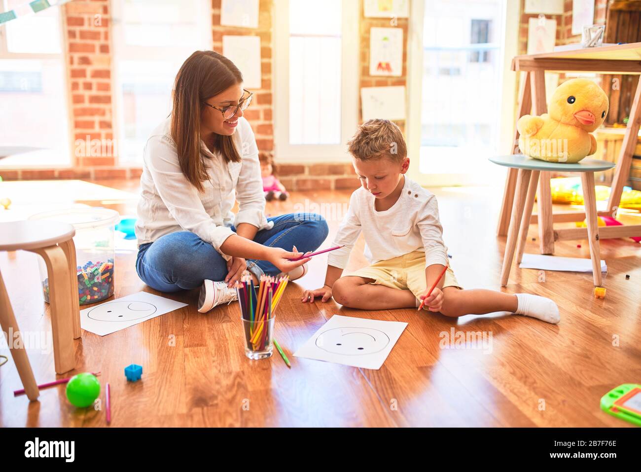 Beautiful teacher and toddler drawing using pencils and paper around ...
