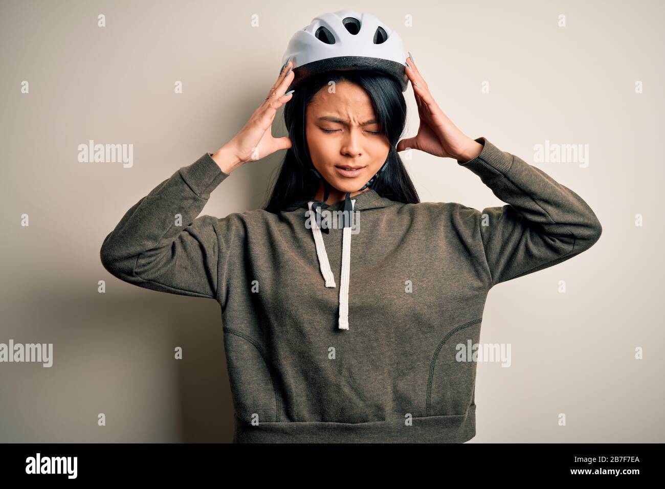Young beautiful chinese woman wearing bike helmet over isolated white ...