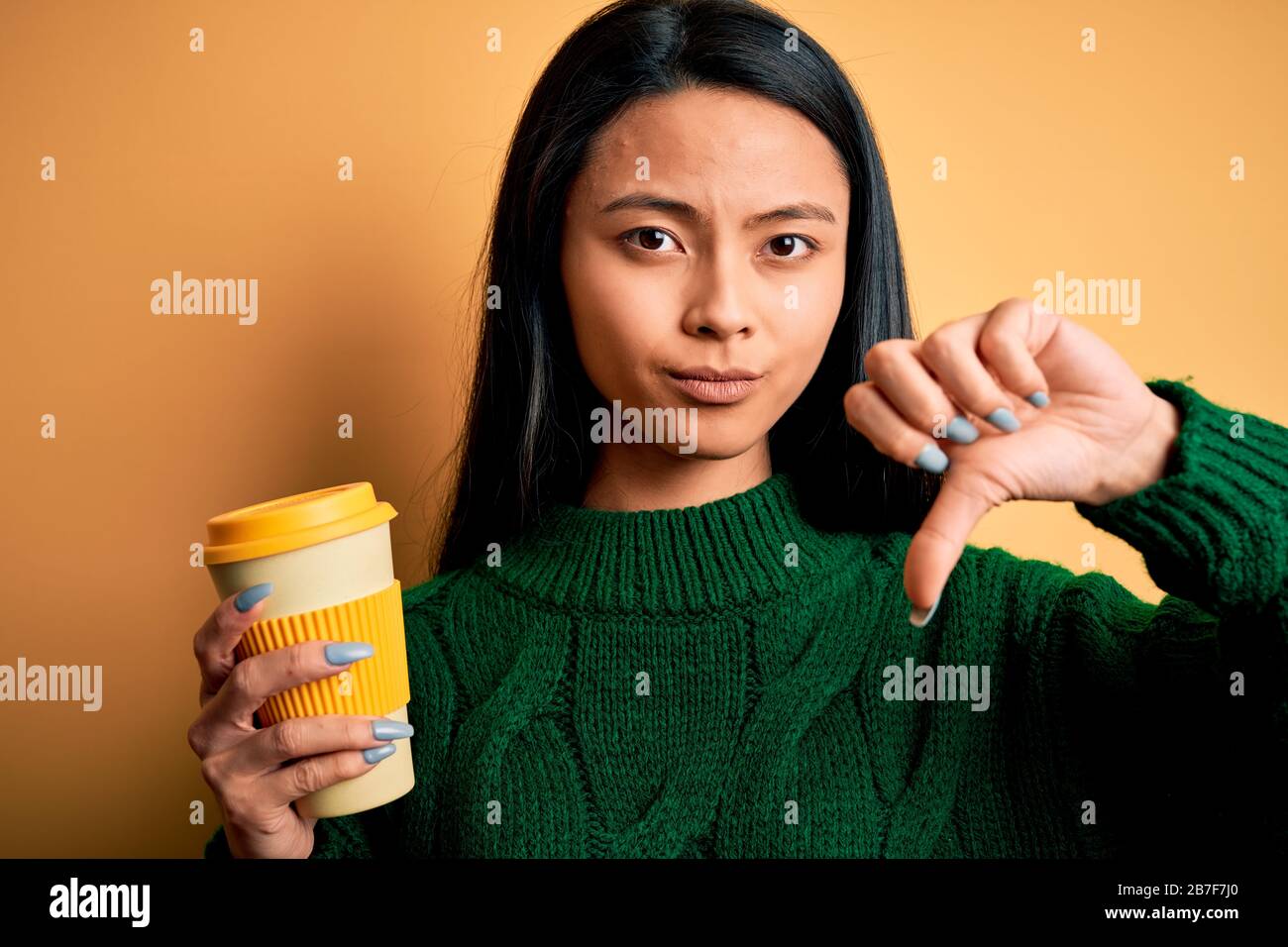 Young beautiful chinese woman drinking cup of coffee over isolated ...