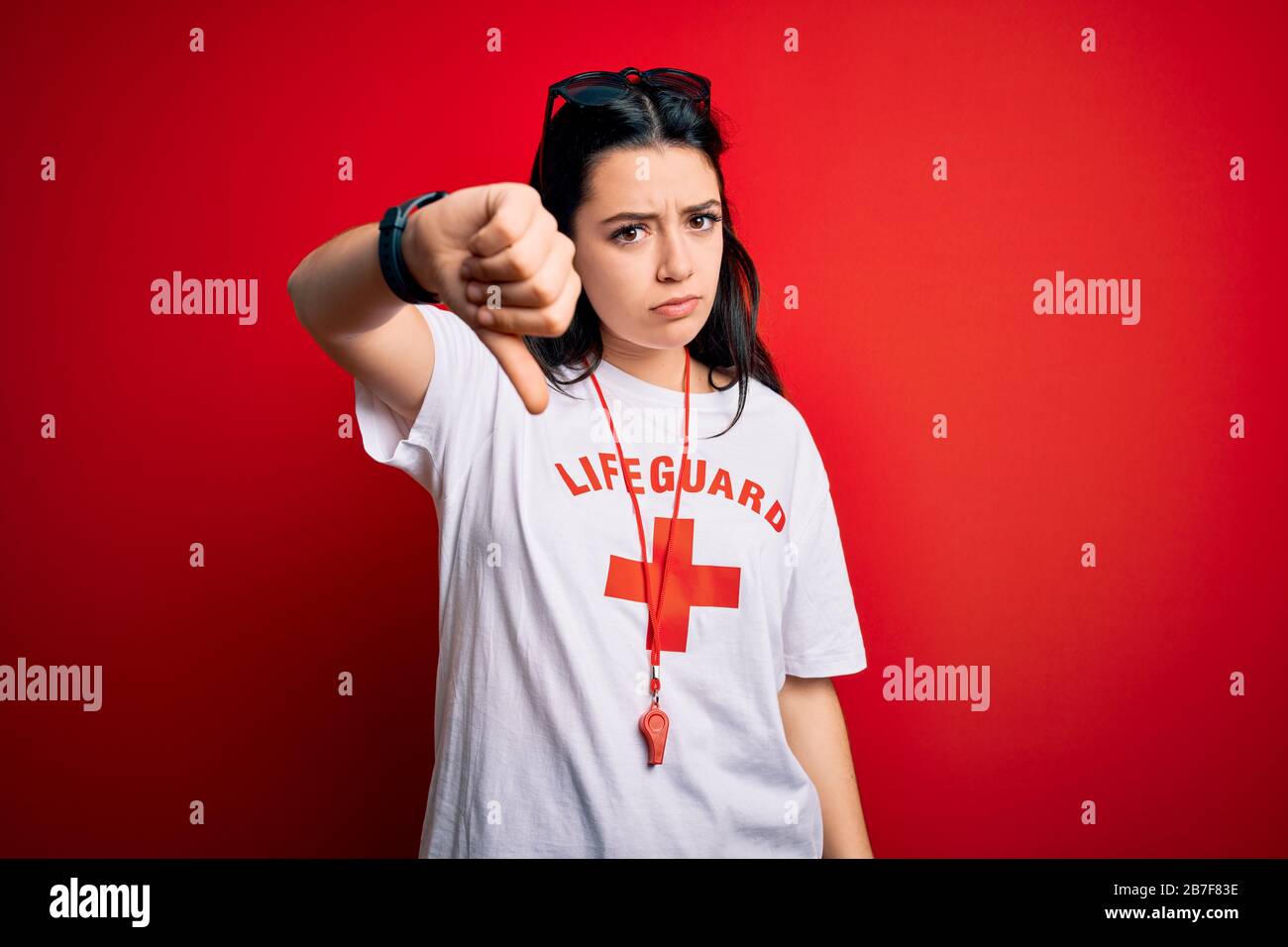 Young lifeguard woman wearing secury guard equipent over red background ...