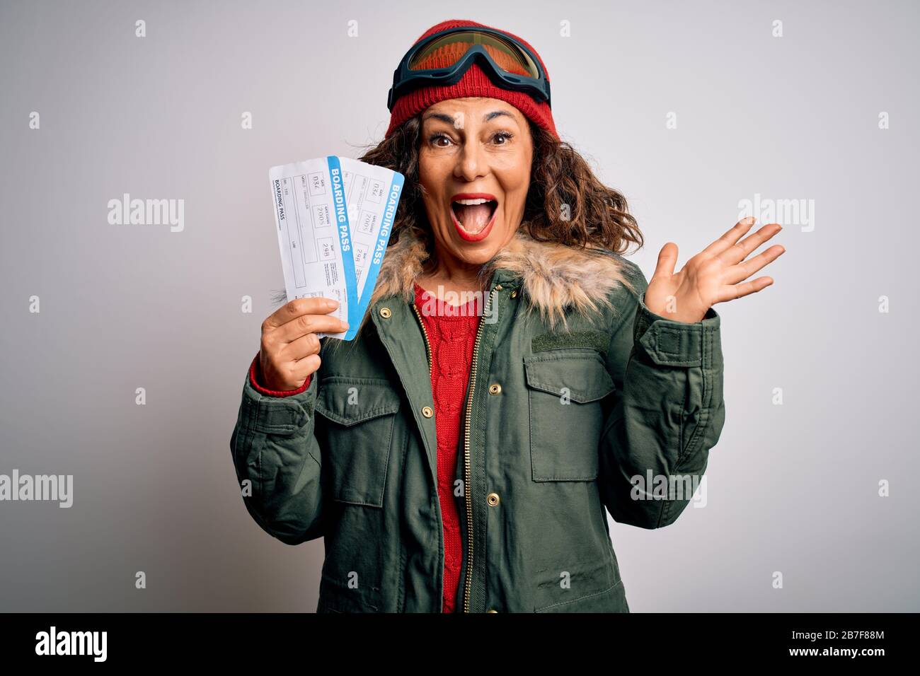 Middle age tourist woman wearing skier goggles holding airline boarding ...