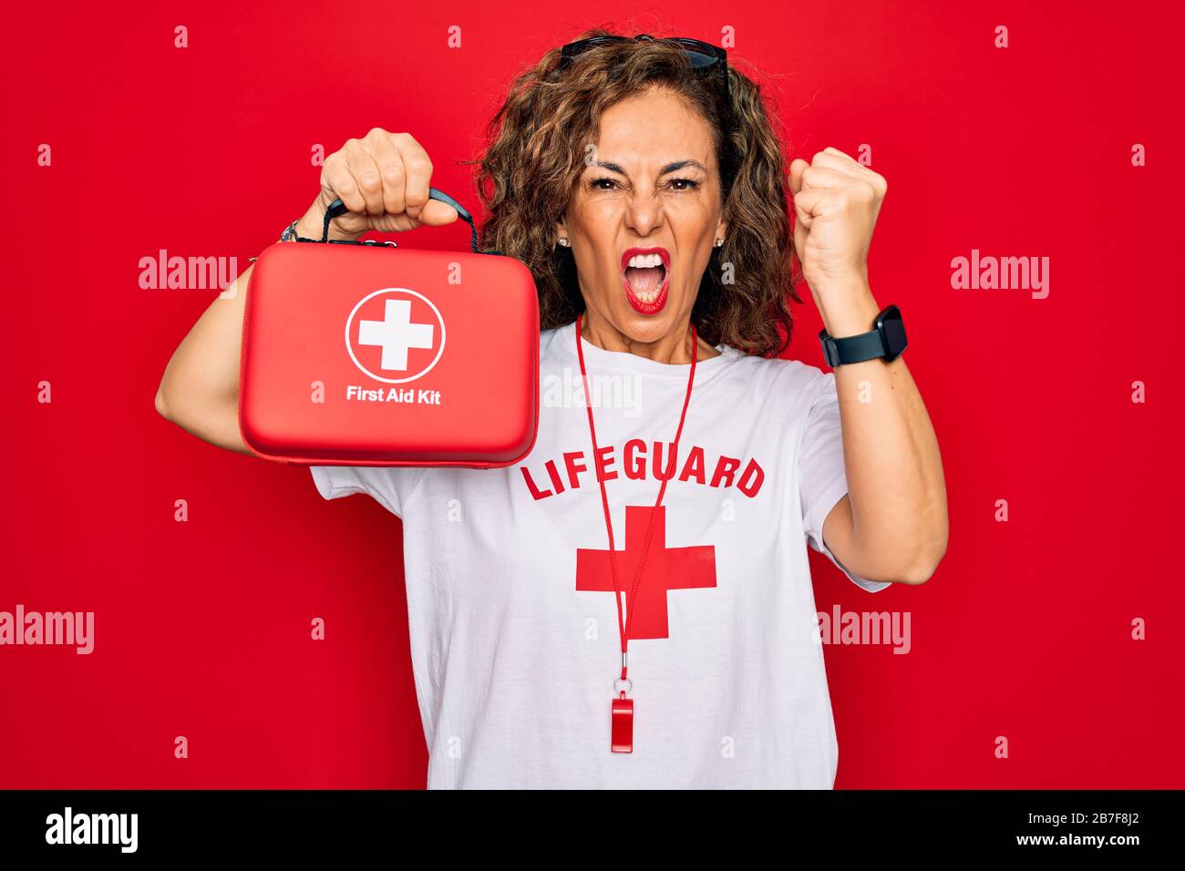 Middle age senior summer lifeguard woman holding first aid kit over red ...