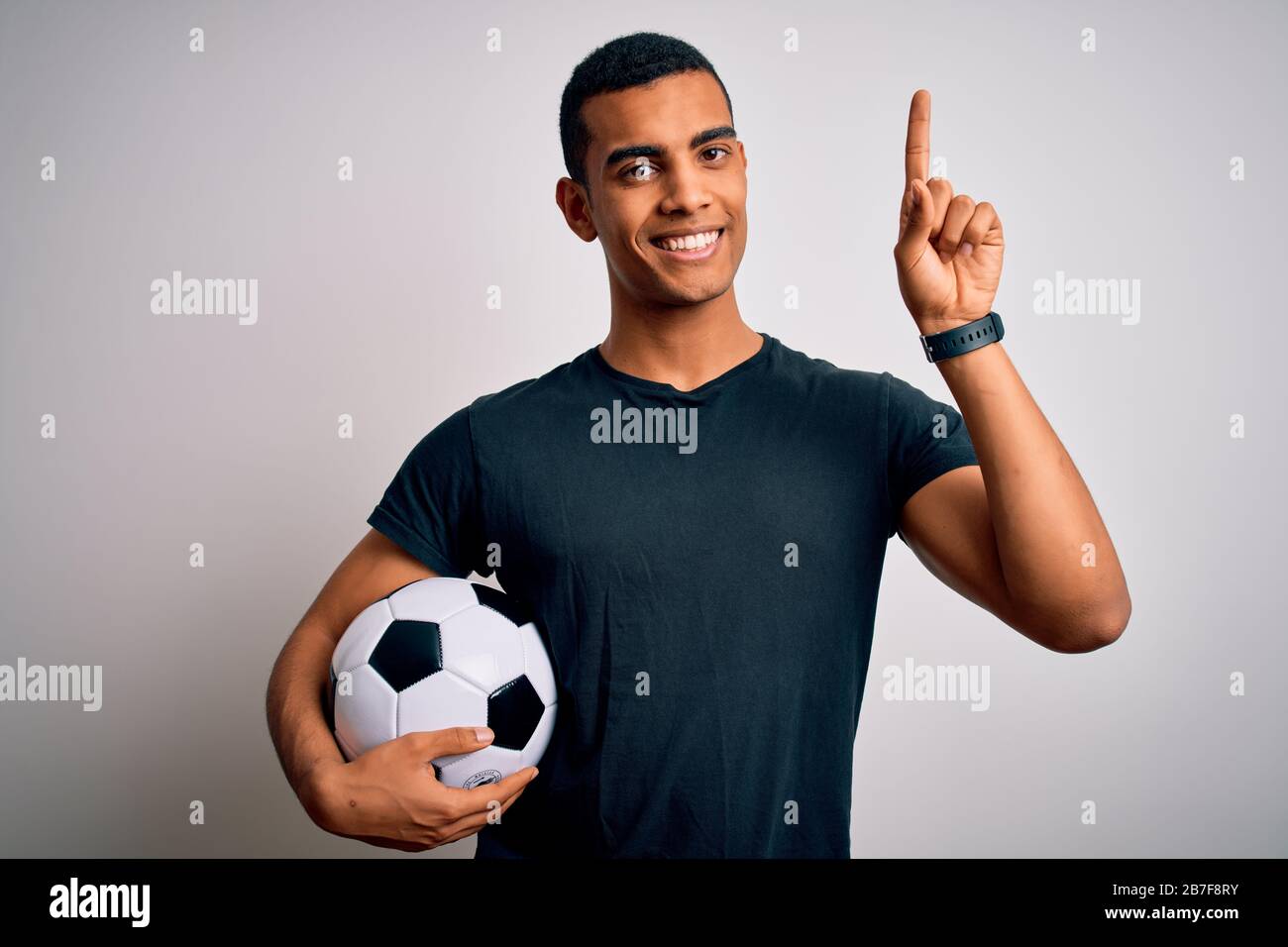 Handsome african american man playing footbal holding soccer ball over ...