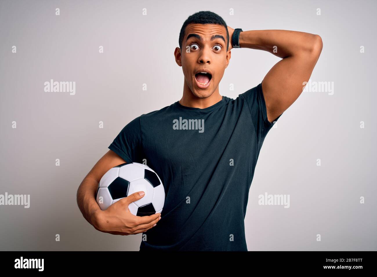 Handsome african american man playing footbal holding soccer ball over ...