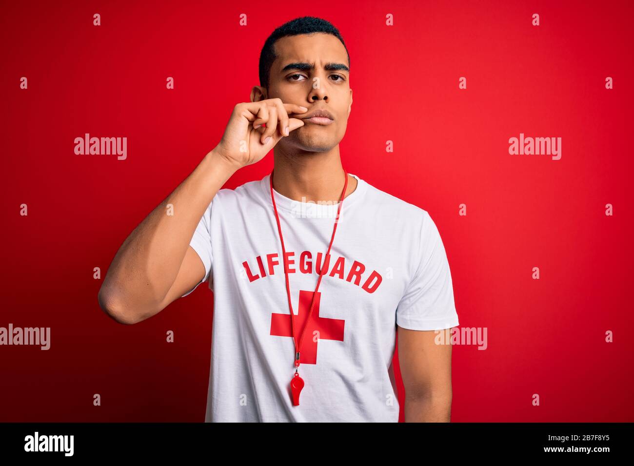 Young handsome african american lifeguard man wearing t-shirt with red ...