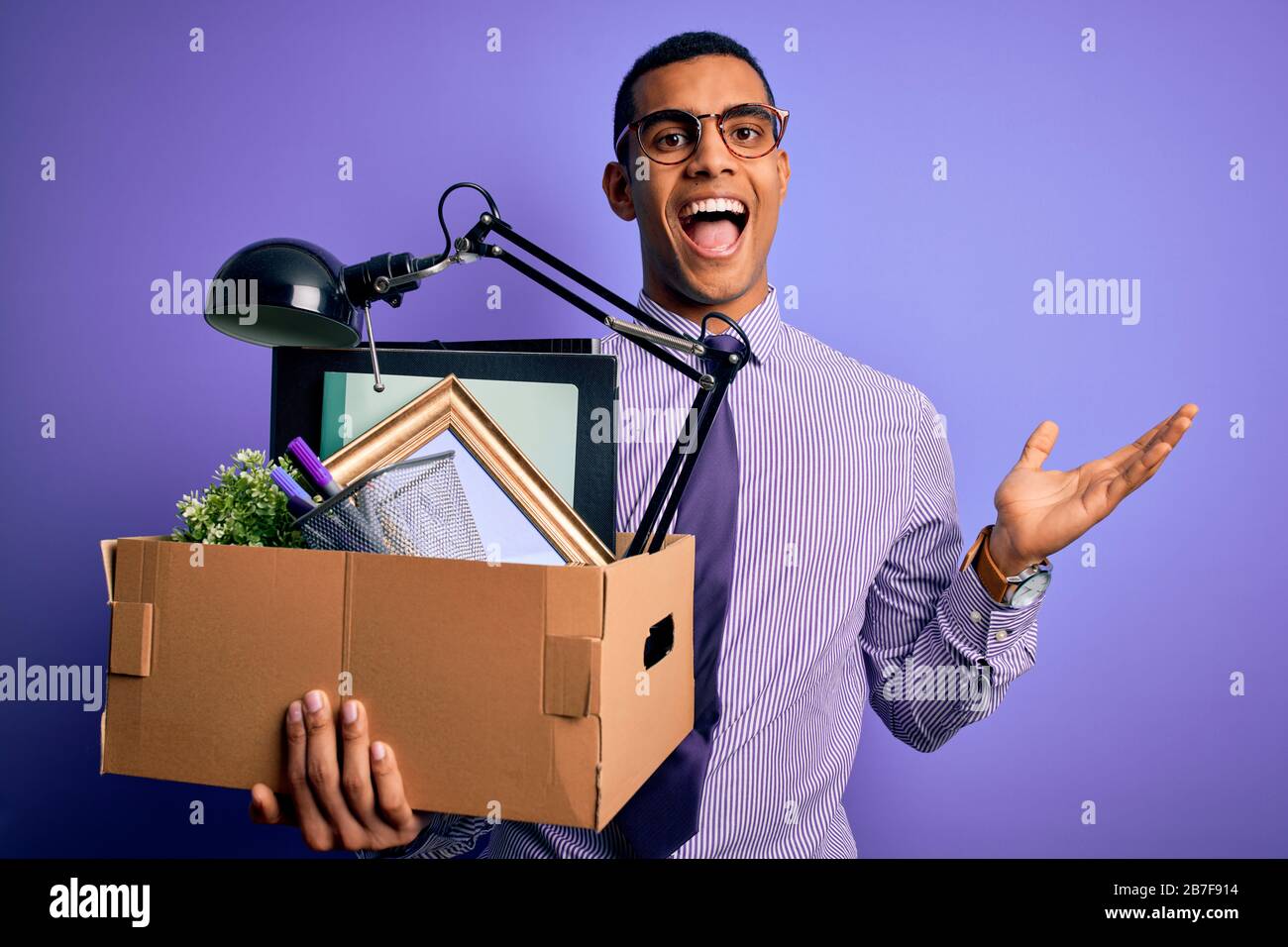 Handsome african american man fired holding box with work objects over ...