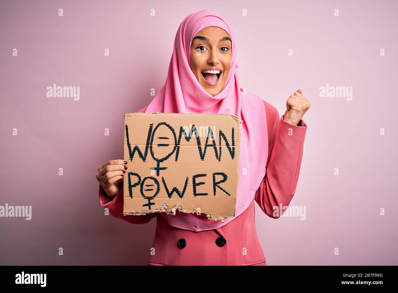 Young activist arab woman wearing pink muslim hijab holding banner with ...