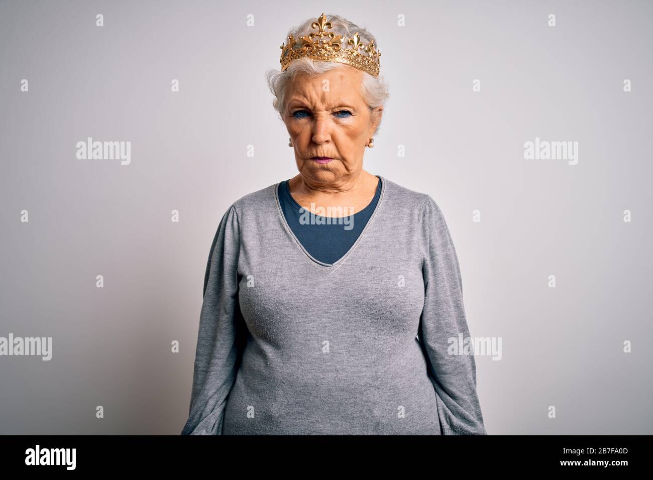 Senior beautiful grey-haired woman wearing golden queen crown over ...