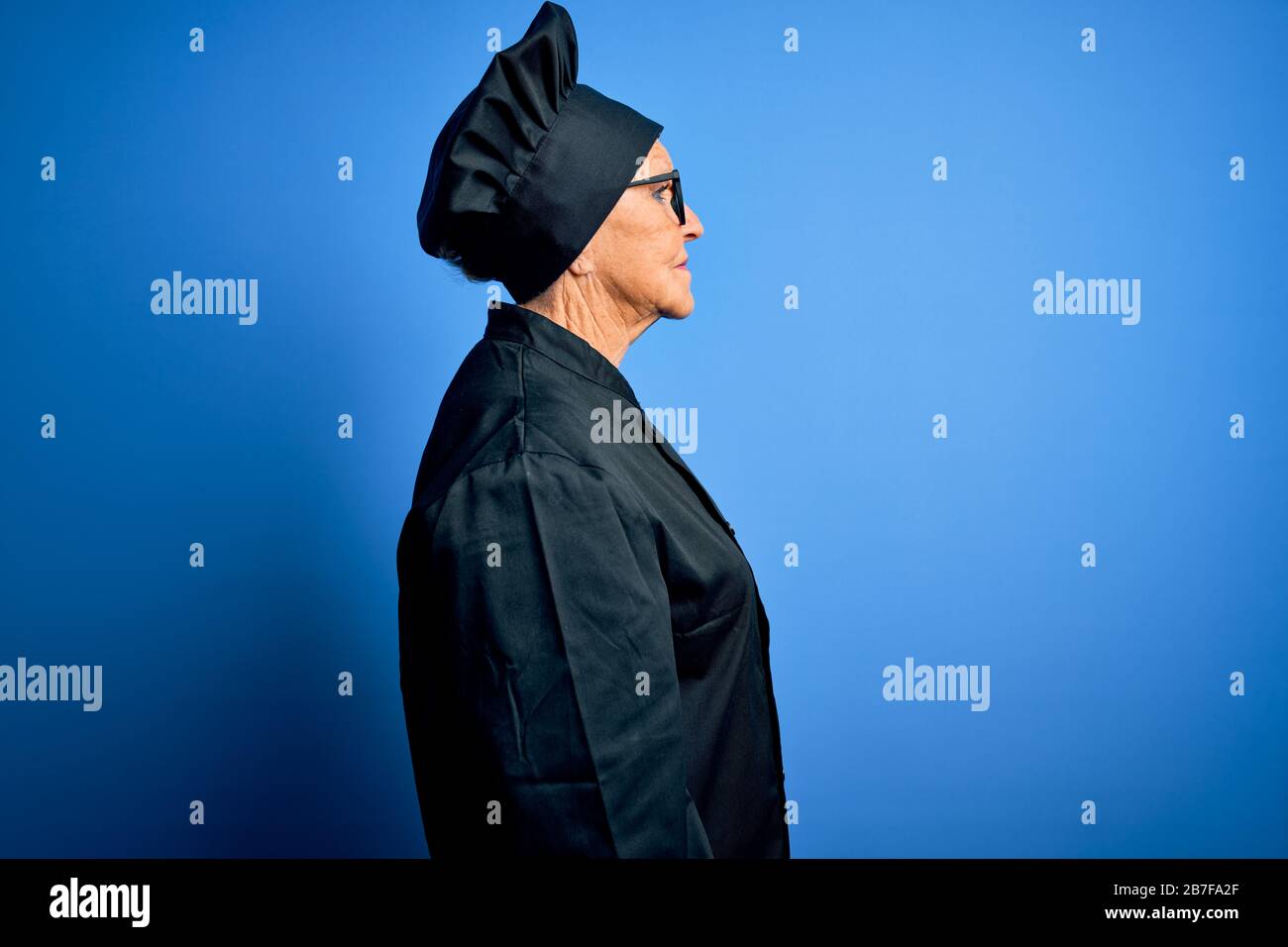 Senior beautiful grey-haired chef woman wearing cooker uniform and hat ...