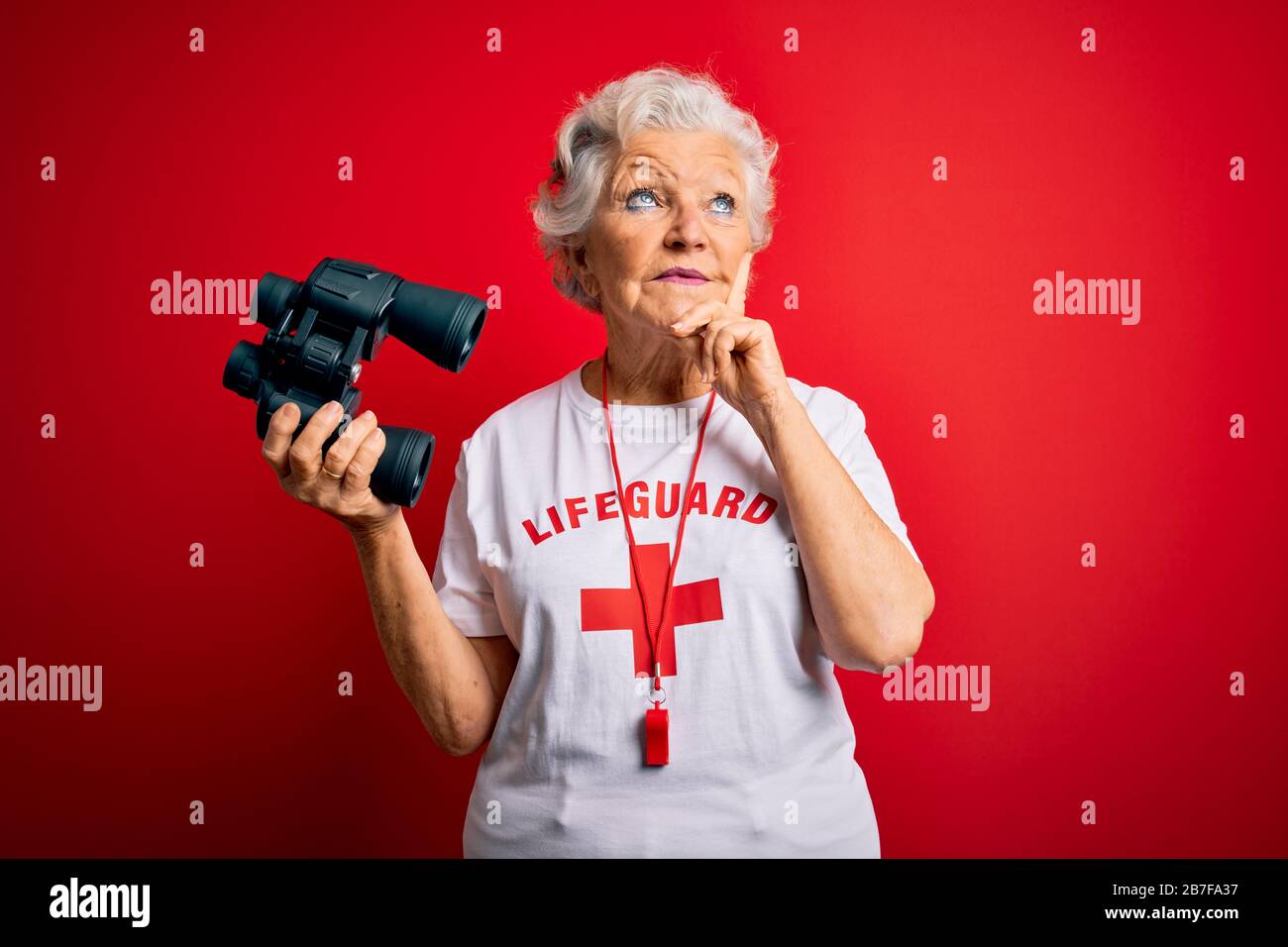 Senior beautiful grey-haired lifeguard woman using binoculars and ...