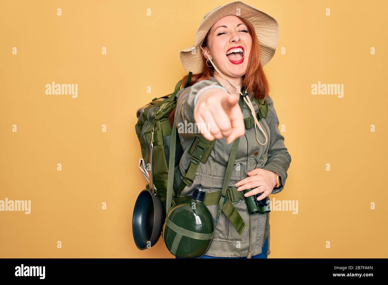 Young redhead backpacker woman hiking wearing backpack and hat over ...