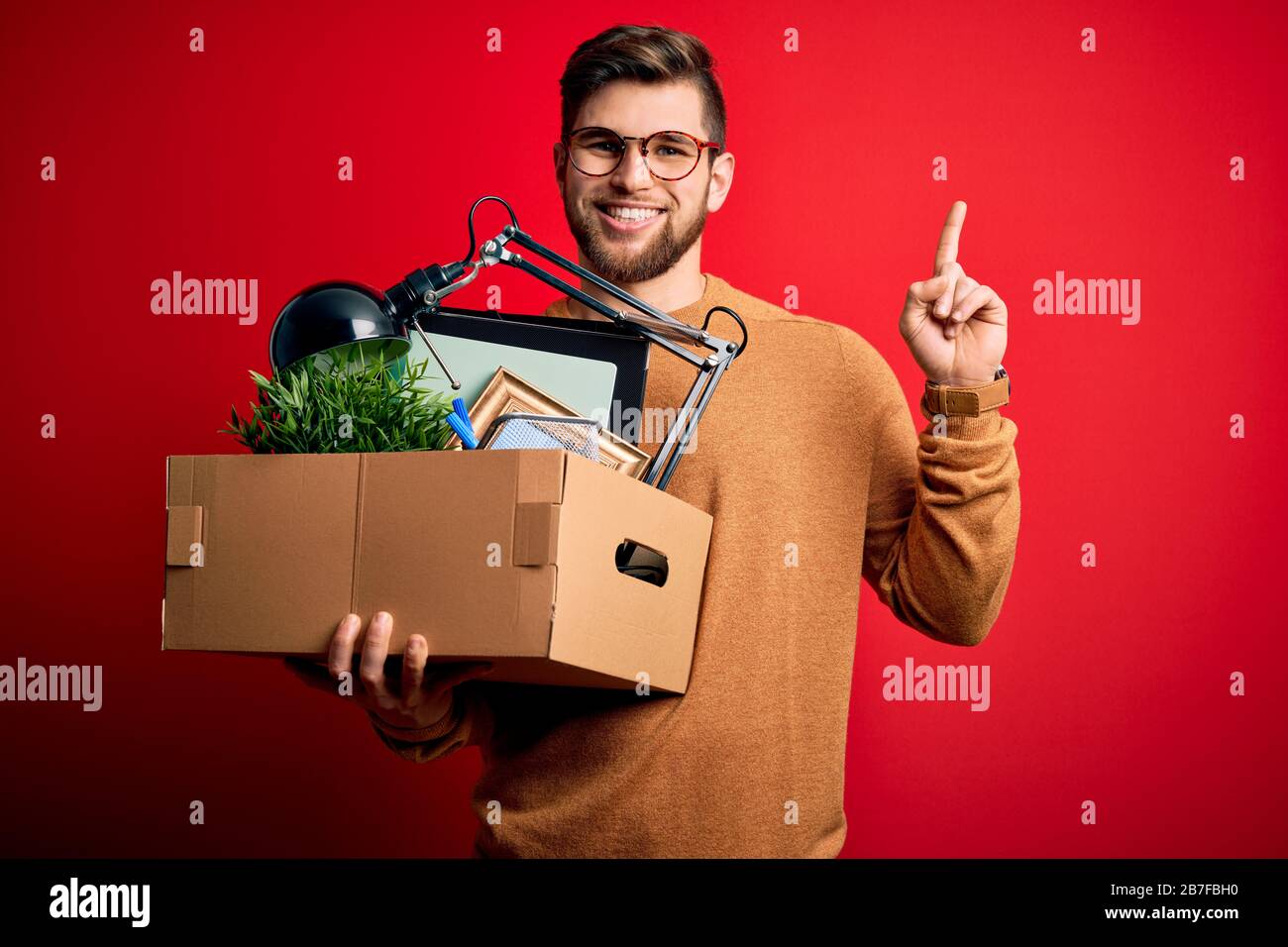 Young blond worker man with beard and blue eyes fired holding cardboard ...