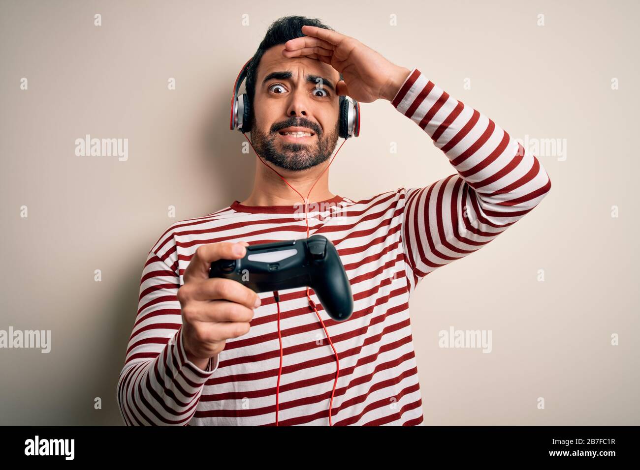Young handsome gamer man with beard playing video game using joystick ...