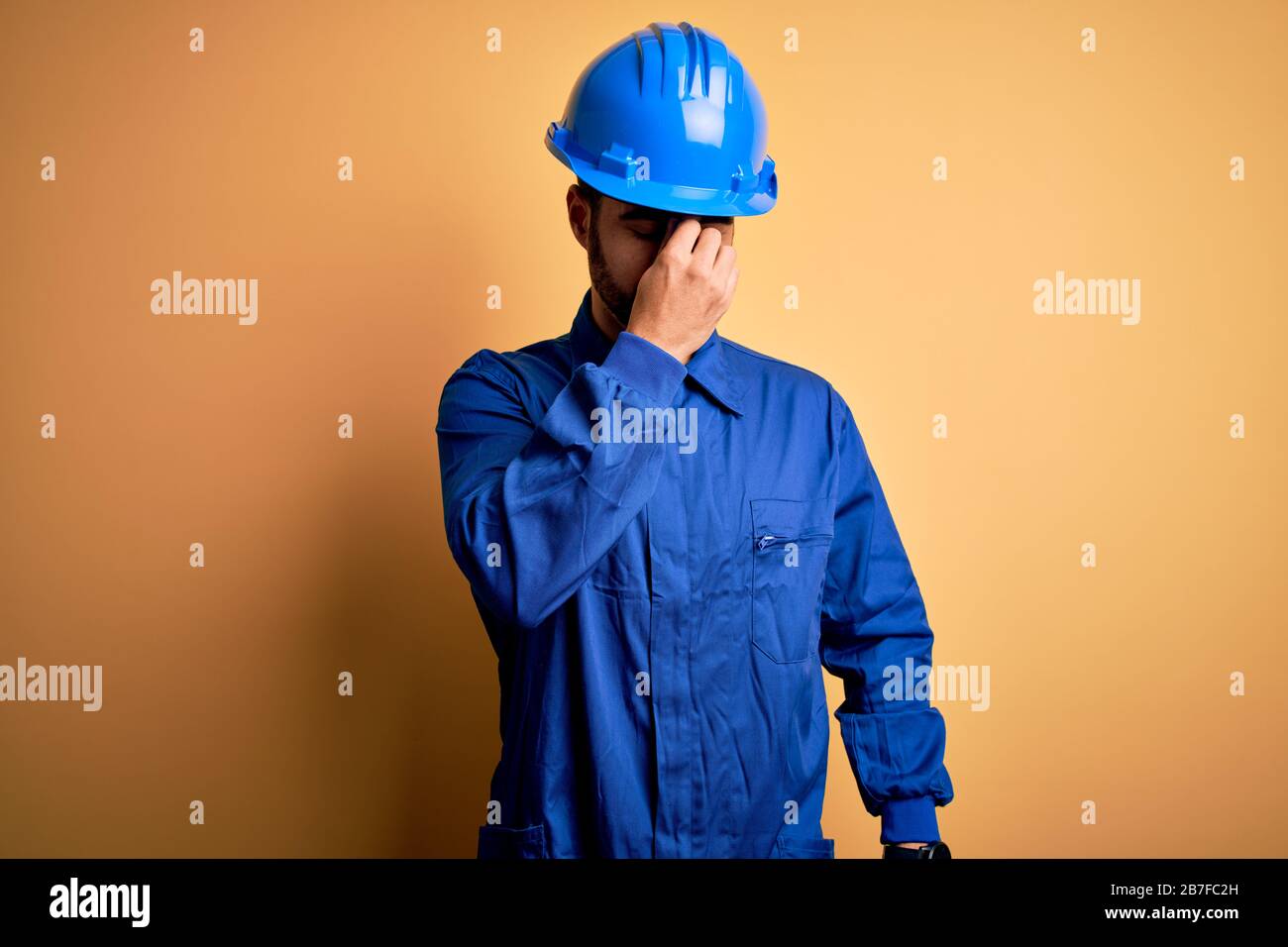 Mechanic man with beard wearing blue uniform and safety helmet over ...
