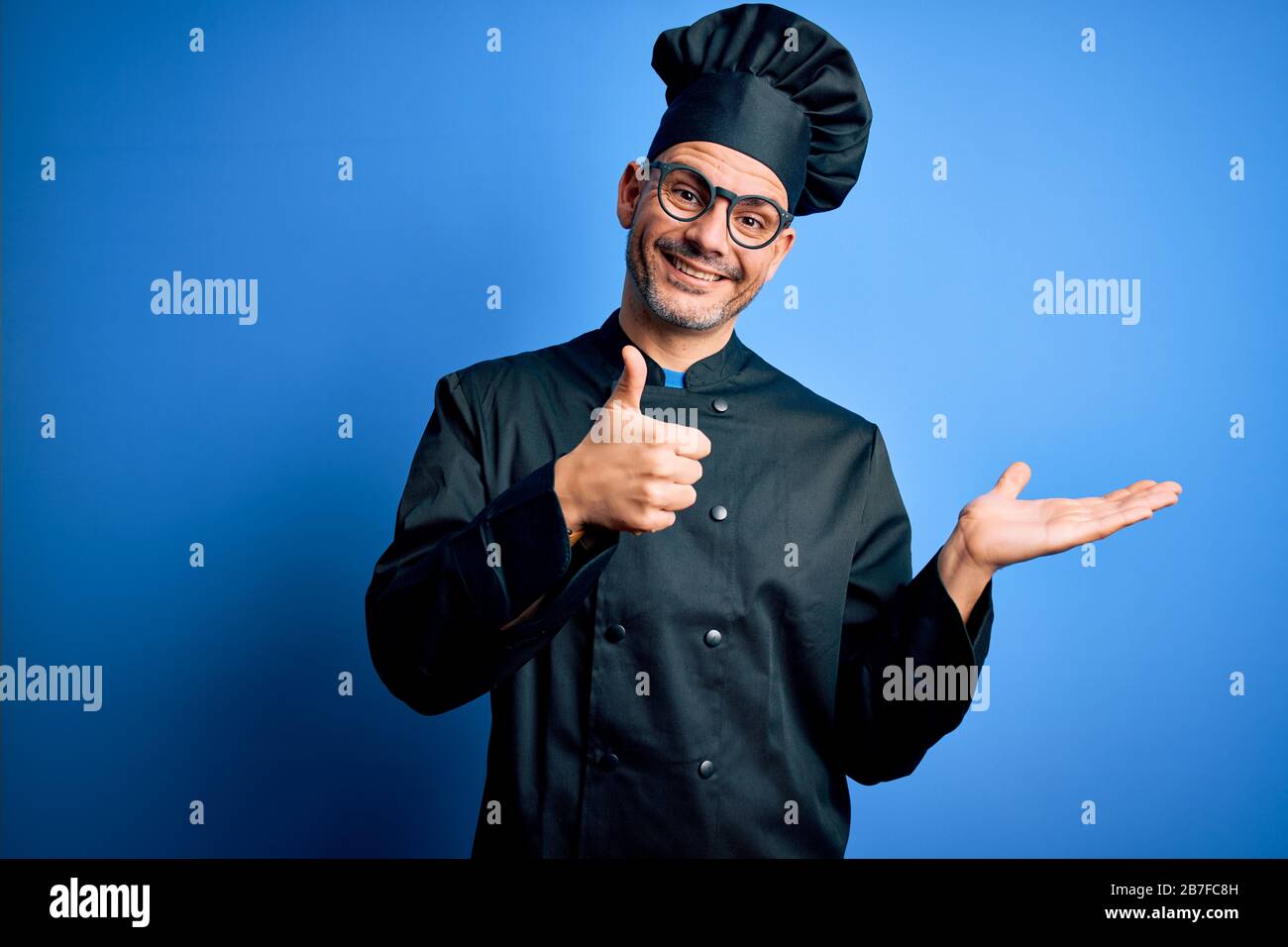 Young handsome chef man wearing cooker uniform and hat over isolated ...