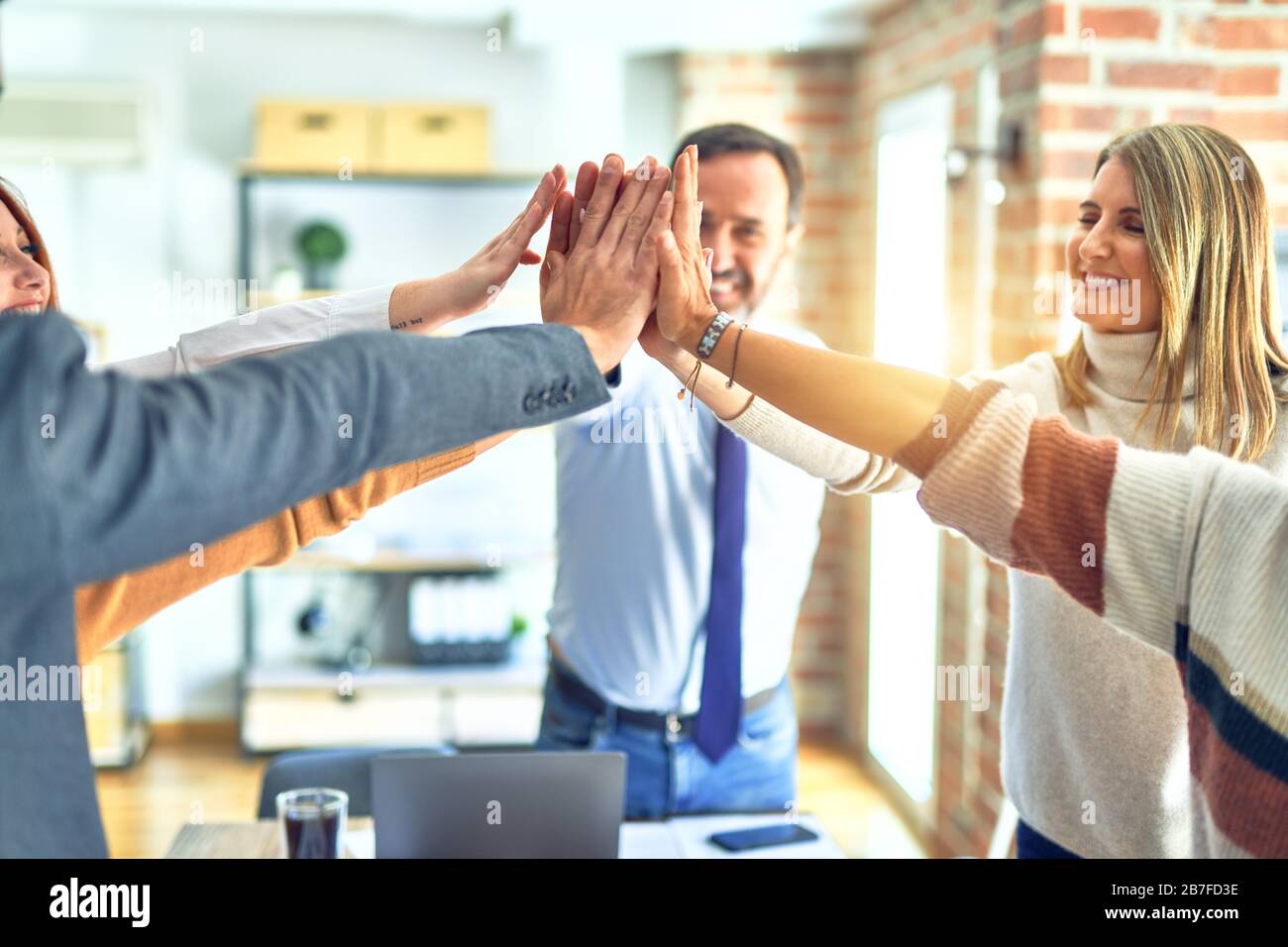 Group of business workers standing with hands together highing five at ...