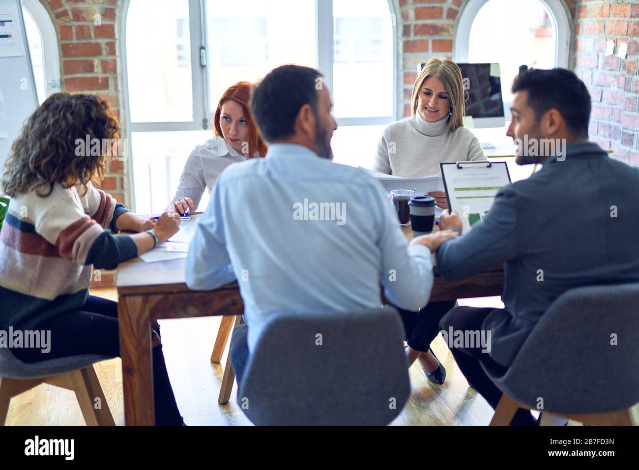 Group of business workers working together. Sitting on desk using ...