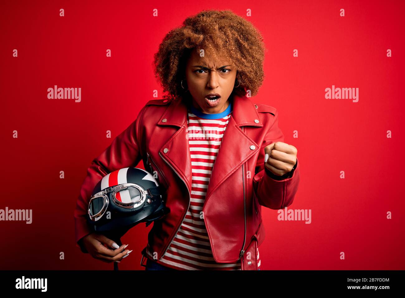 Young African American motocyclist woman holding motorcycle helmet over ...
