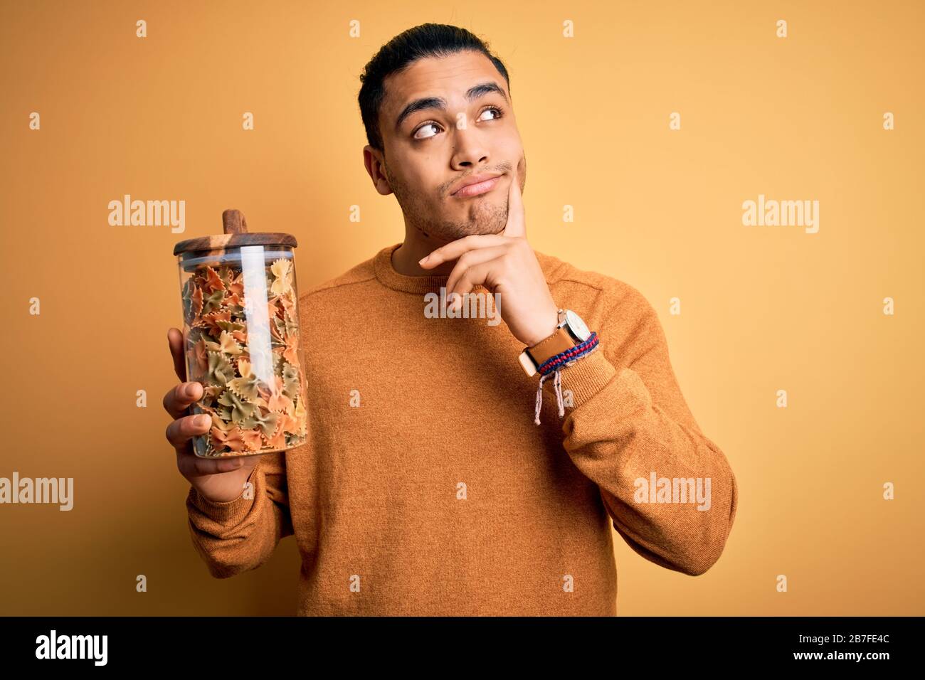 Young brazilian man holding jar with Italian dry pasta over isolated ...