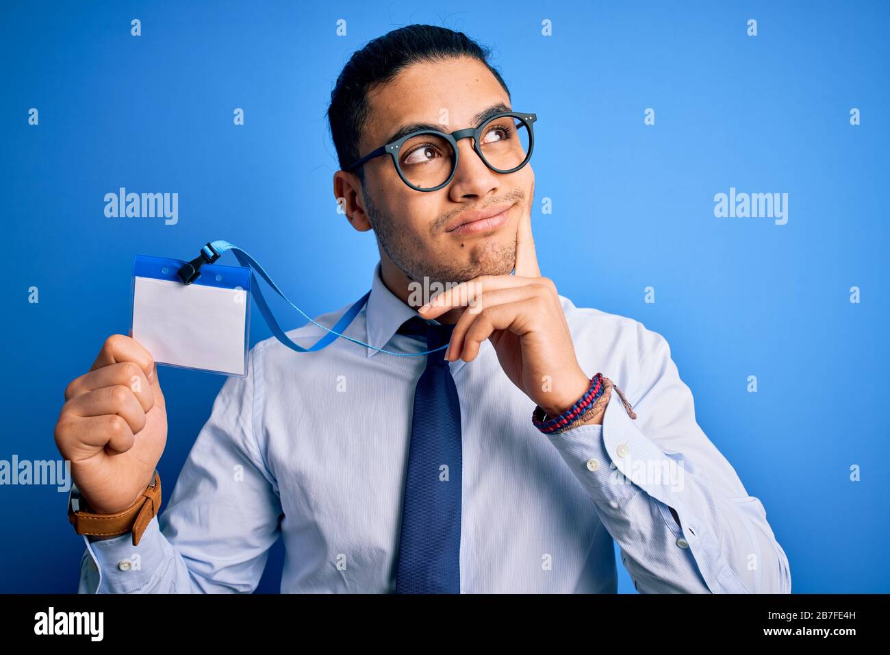 Young brazilian call center agent man holding id identification card ...