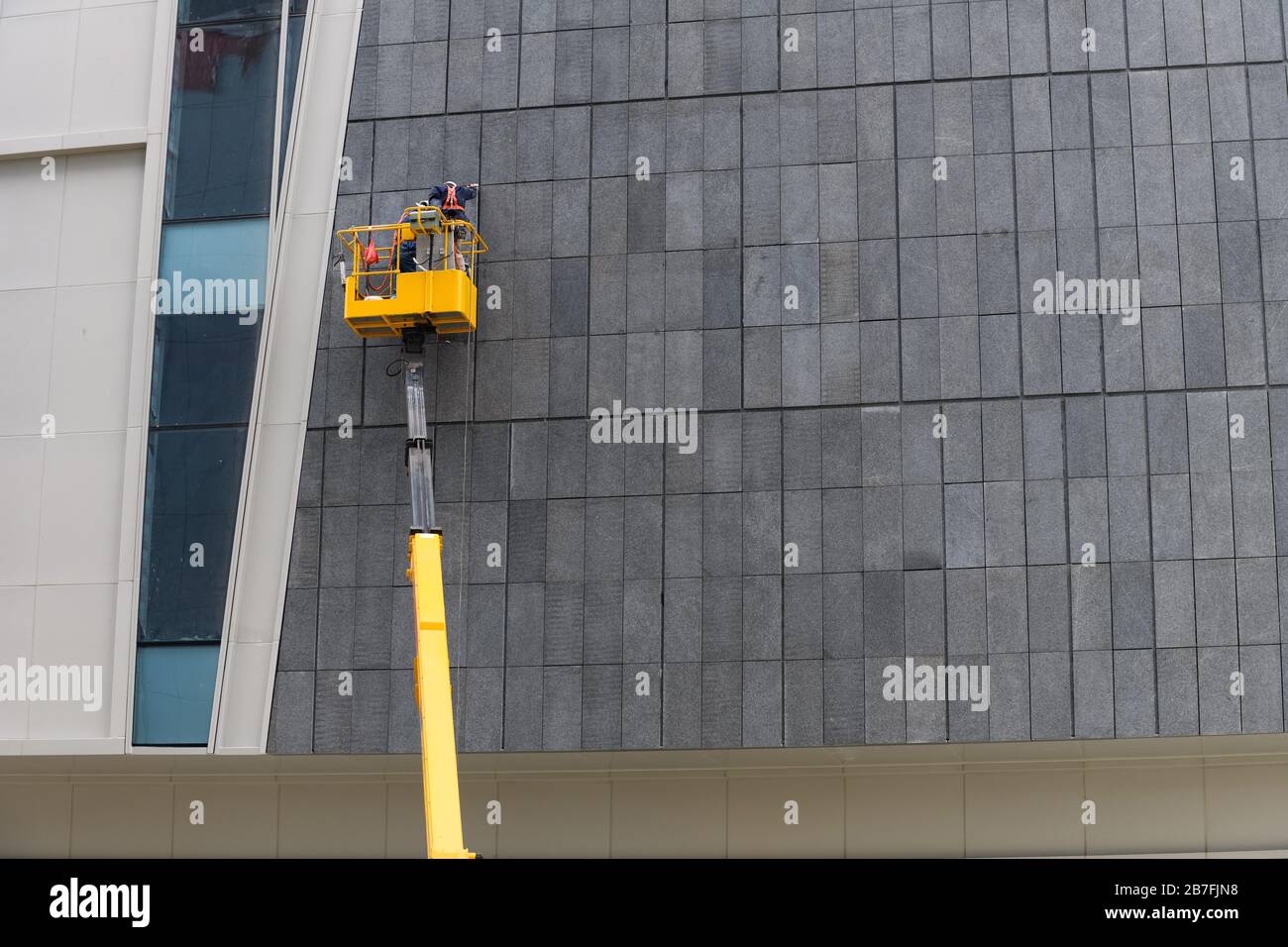 workers repairing the outside of a commercial building horizontal ...