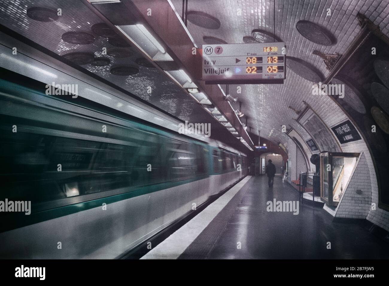 A train departs Pont Neuf La Monnaie Metro station as a passenger exits ...