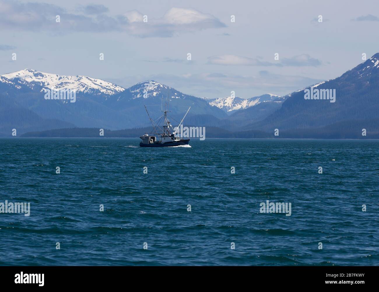 Commercial fishing boat in Southeast Alaska with mountains in the ...