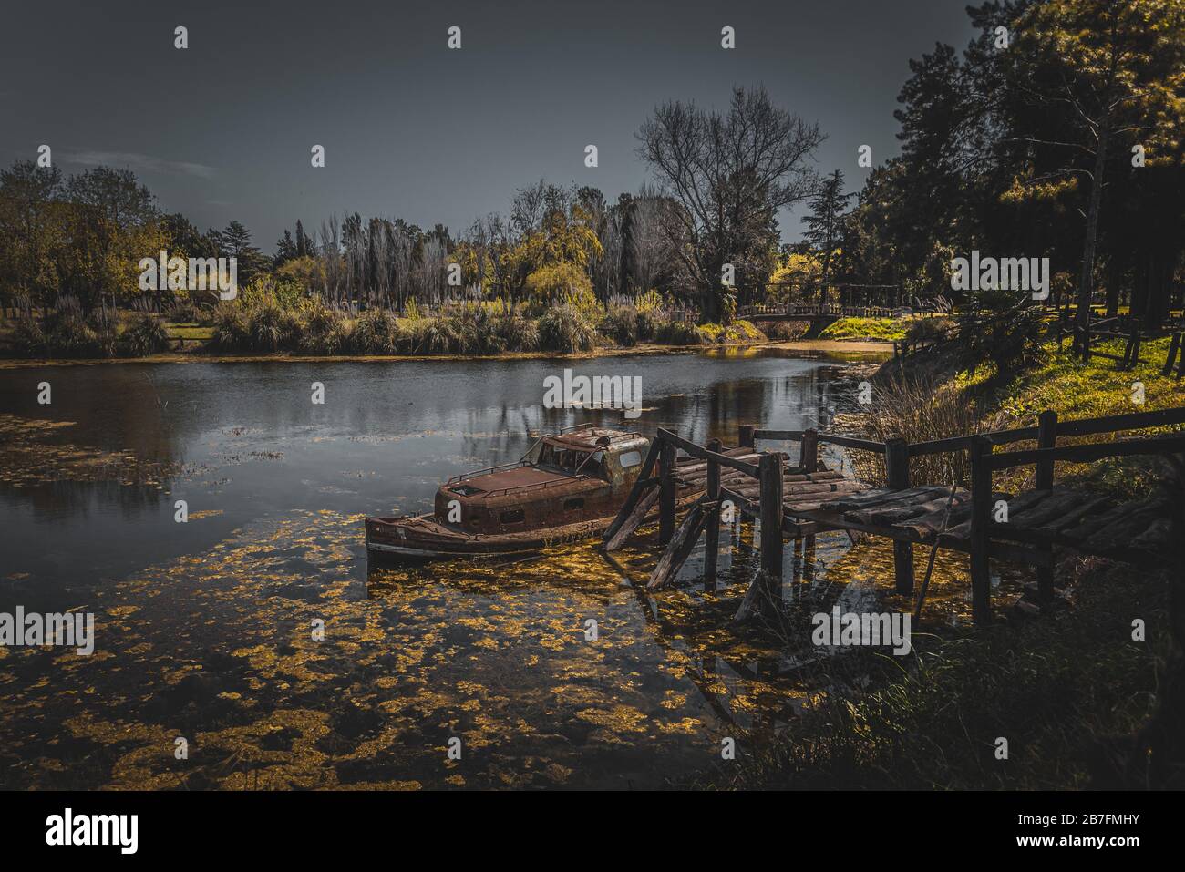 Old rusty abandoned wrecked ship tied up to a broken wooden dock in a ...