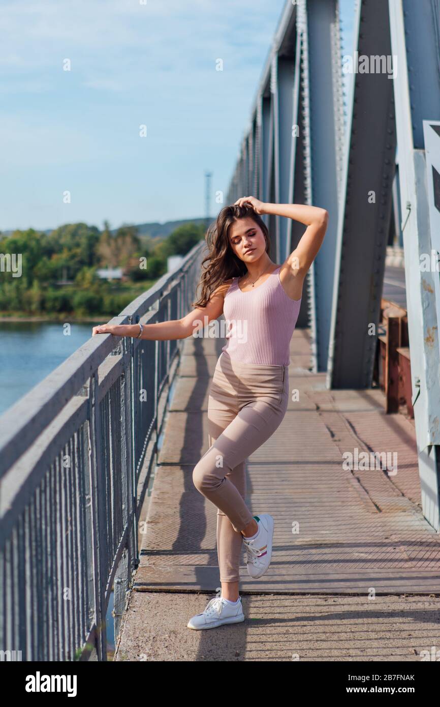 Pretty young woman posing on the old rusty transport bridge over the river during sunset Stock ...