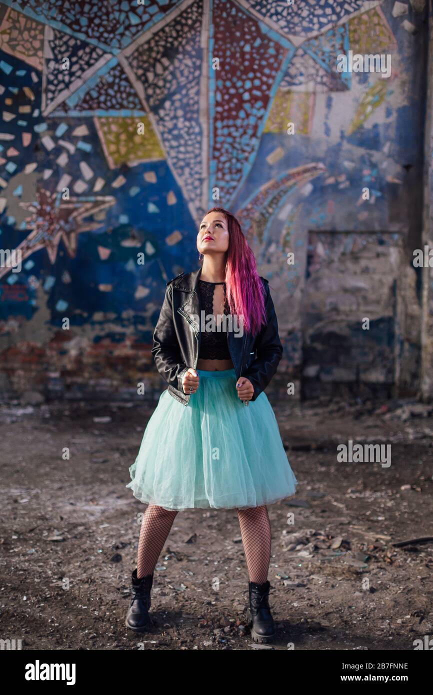 Portrait of a young girl with pink hair standing inside of collapsed ...