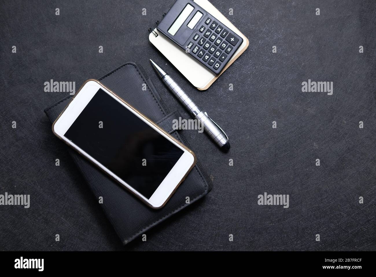 top view of smart phone, notepad and calculator on black background ...