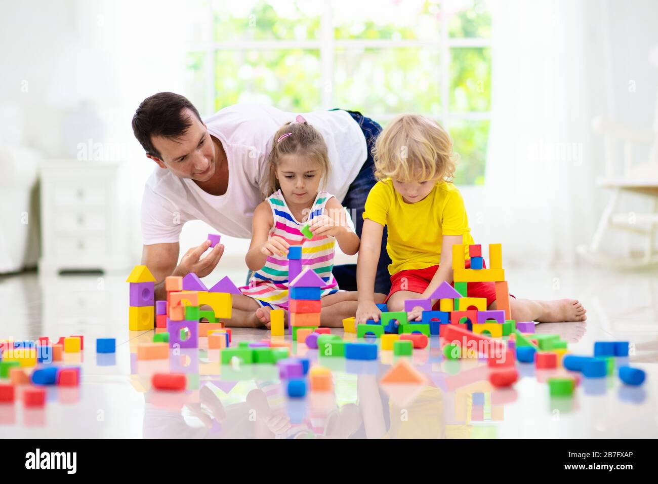 Father and kids play with colorful blocks. Dad, little boy and girl ...