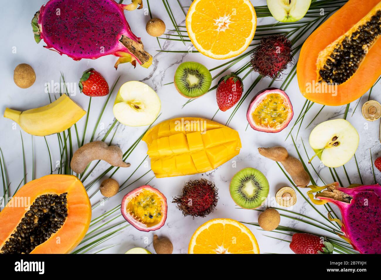 Assortment of different exotic fruits with tropical leaves on white ...