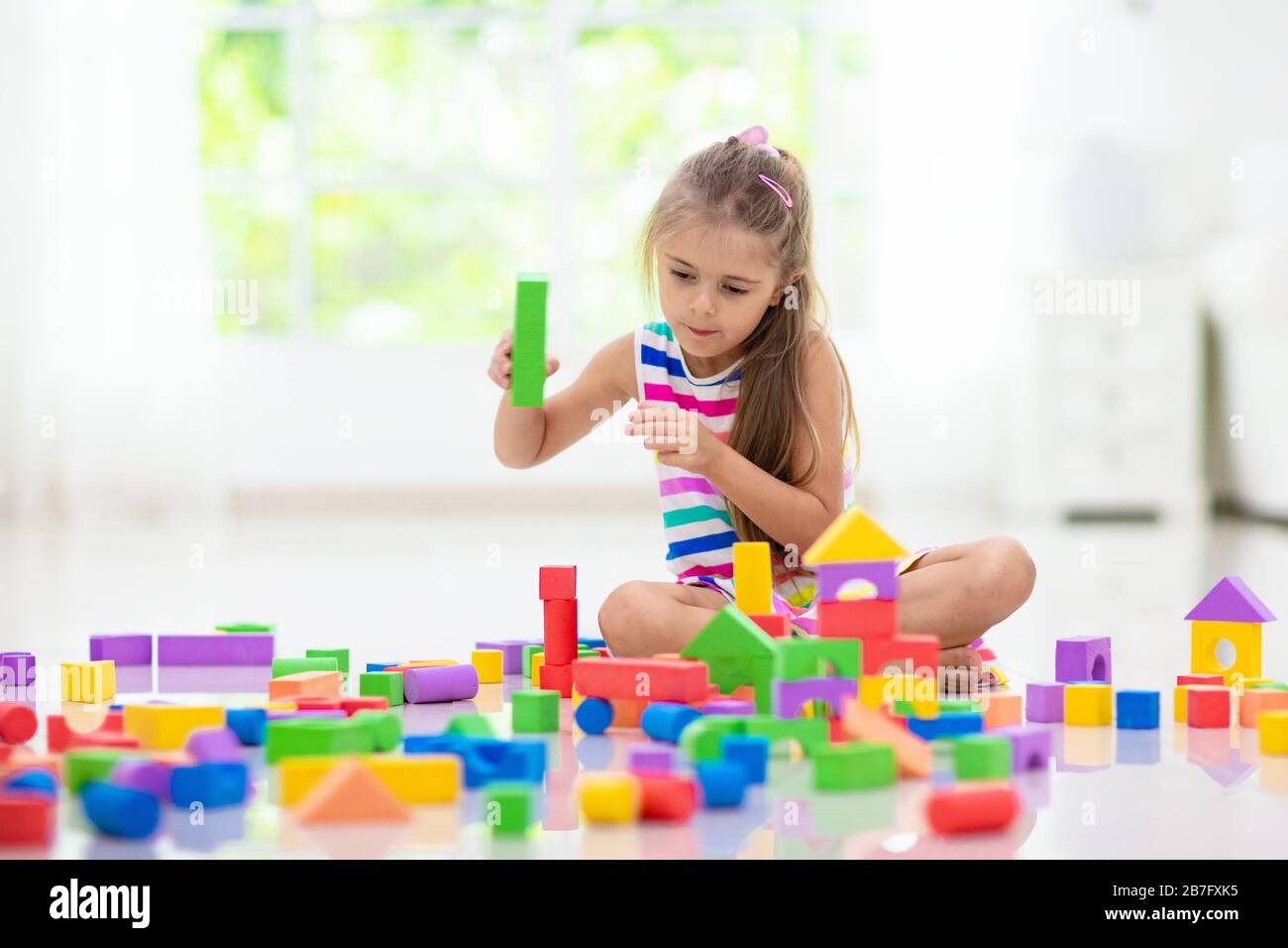 Kids play with colorful blocks. Little girl building tower at home or ...
