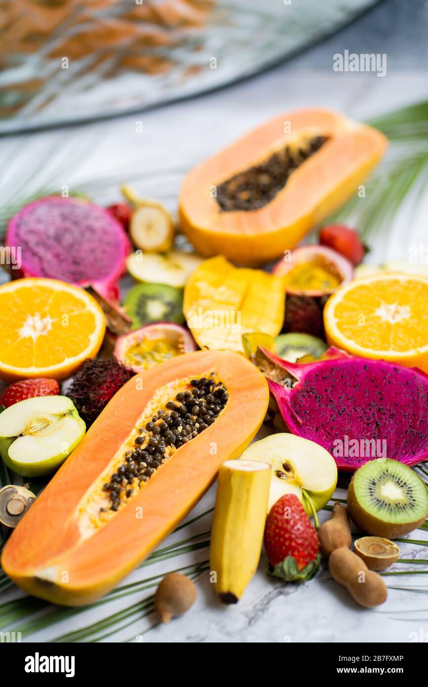 Assortment of different sliced exotic fruits with tropical leaves on ...