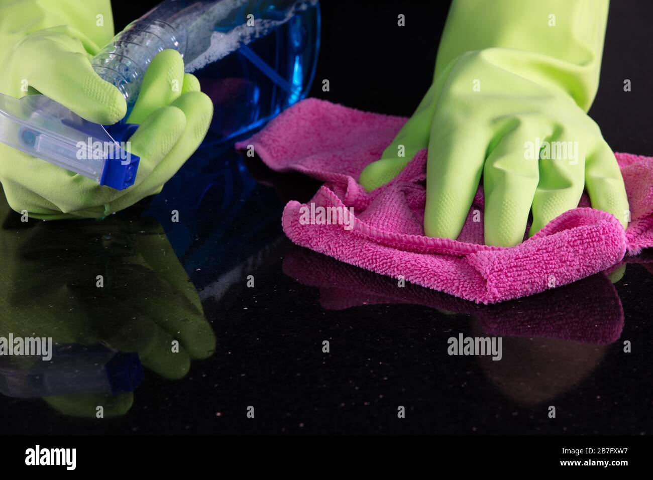 Maid with rubber gloves cleaning the table with a microfiber cloth and ...