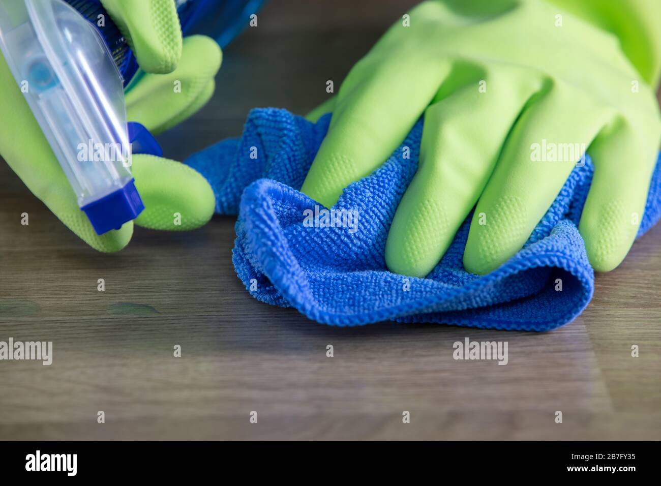 Maid with rubber gloves cleaning the table with a microfiber cloth and ...