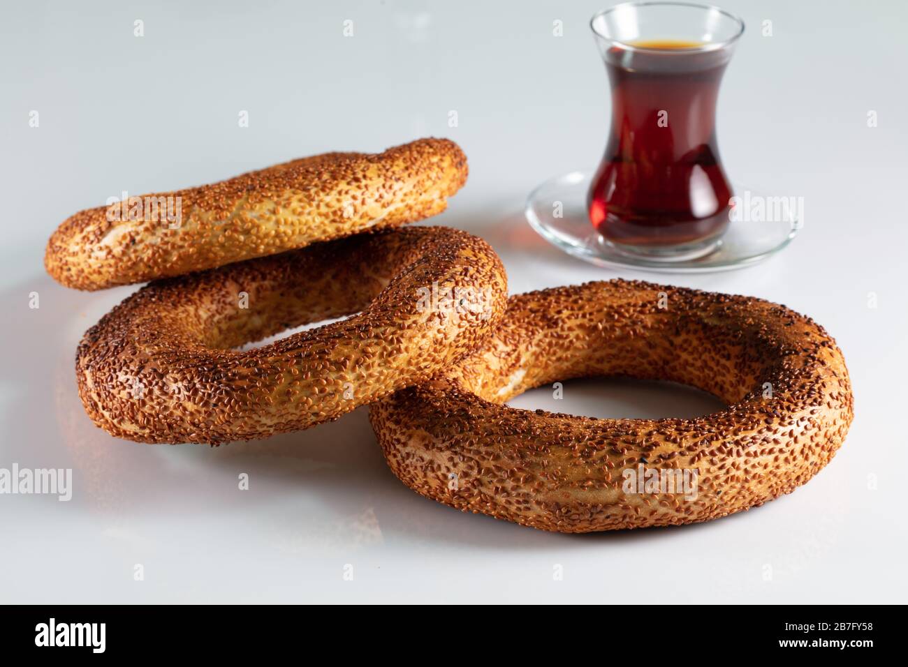 Closeup shot of freshly baked homemade simits with a cup of tea on a white surface Stock Photo ...