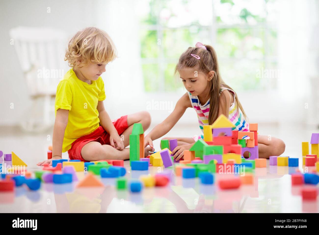 Kids play with colorful blocks. Little boy and girl build tower at home ...