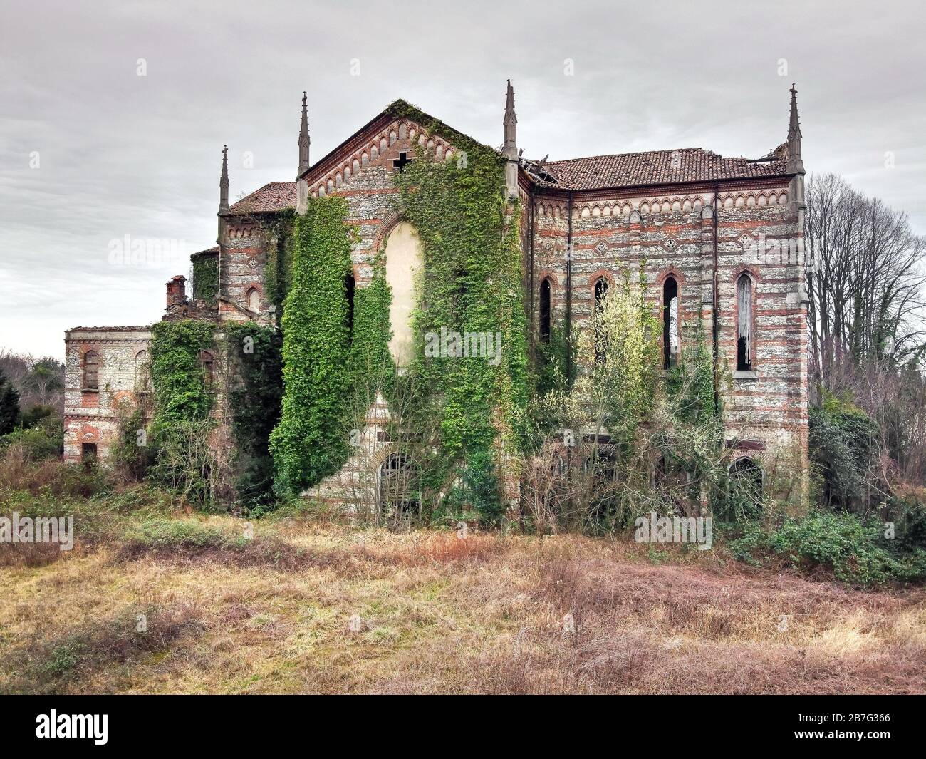 Old abandoned stone church overgrown with weeds and creepers viewed ...