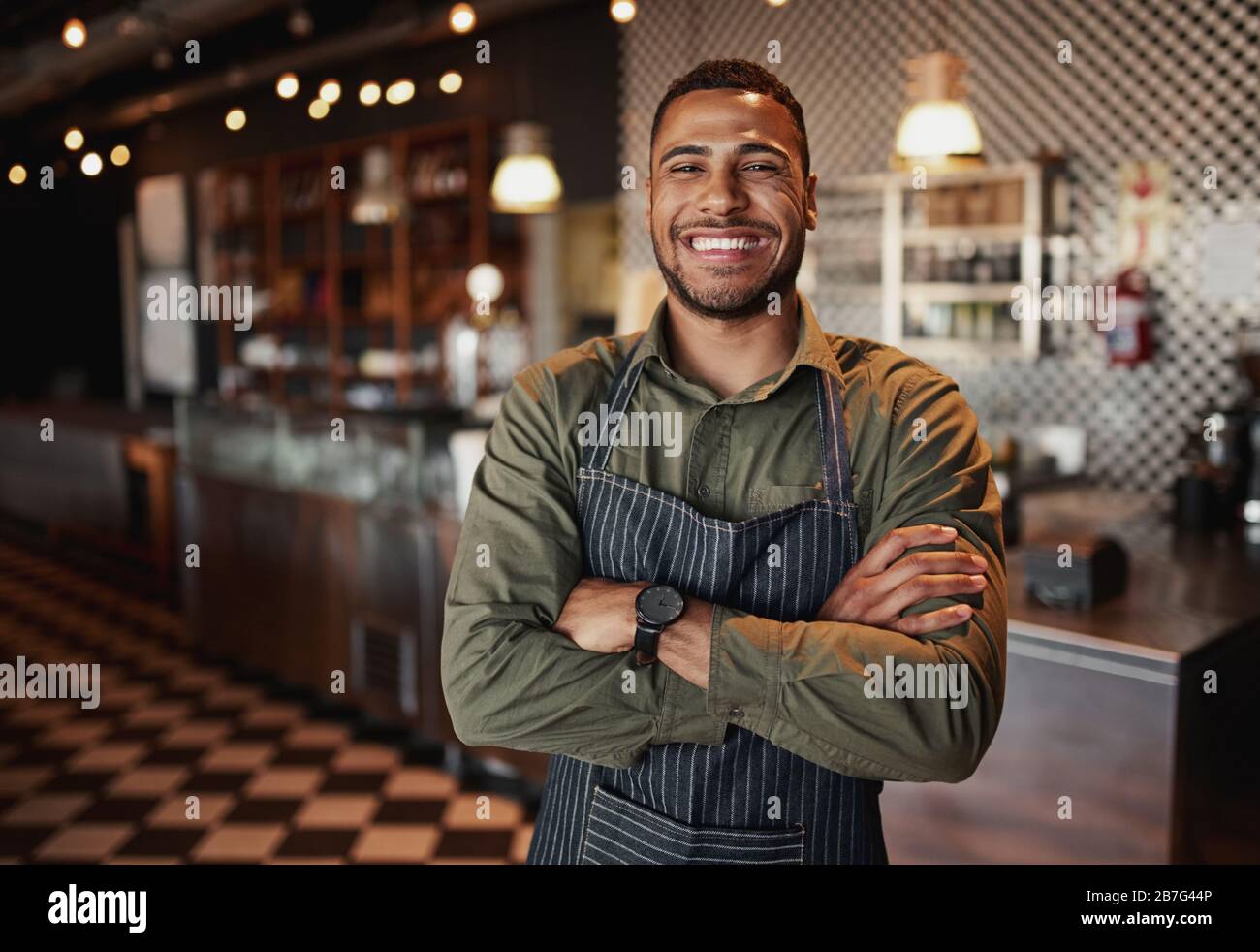 Afro-american cafe owner standing smiling wearing apron with folded ...
