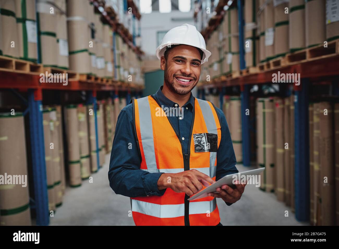 Happy male factory manager using digital tablet in warehouse while ...