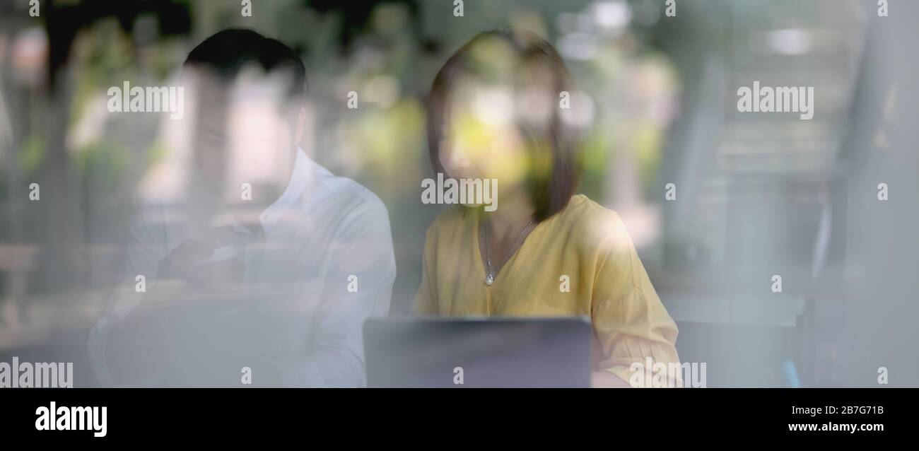 View through glass window of two businesspeople sitting in glass ...