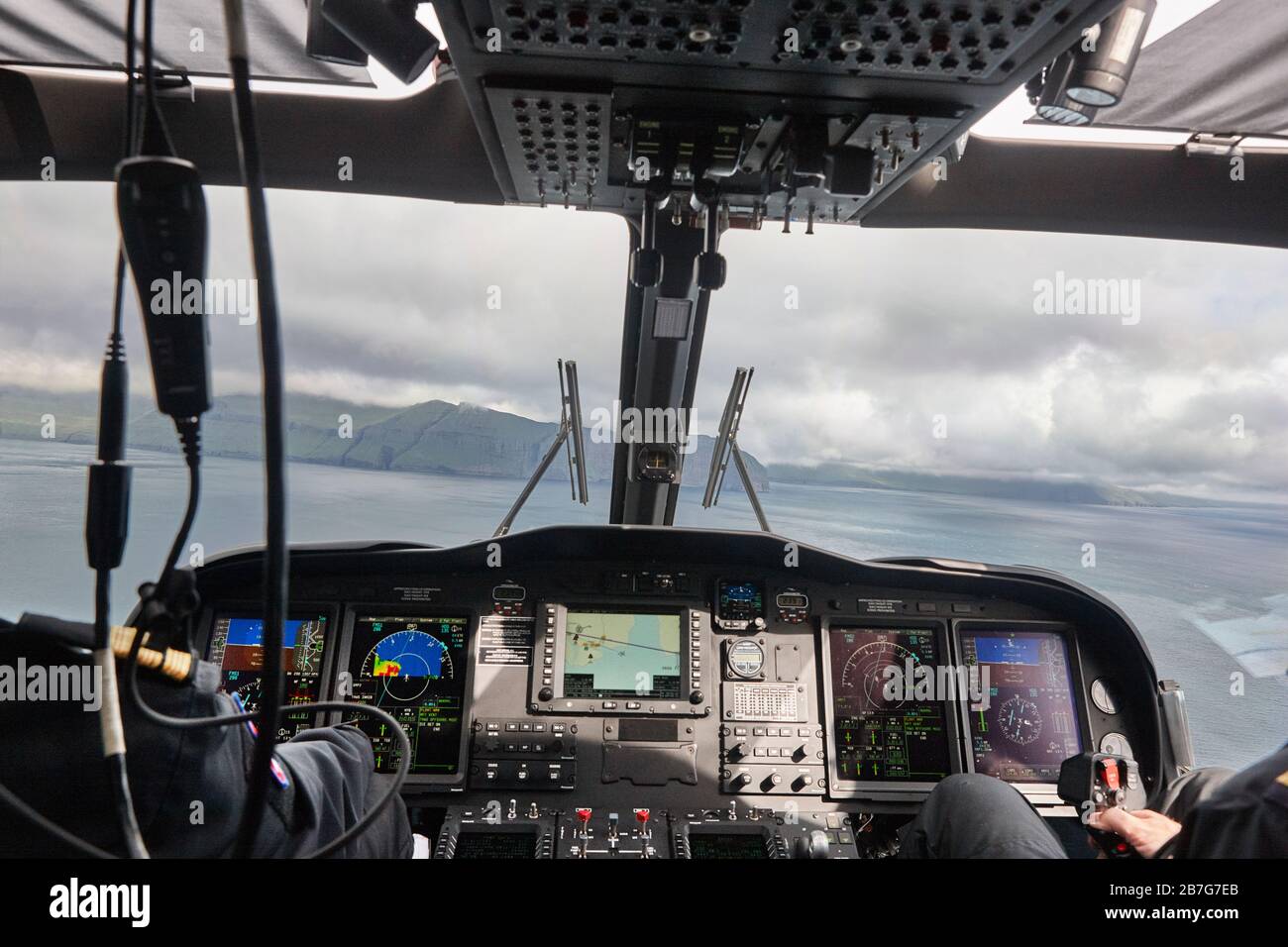Helicopter cabin with pilots flying over Faroe Islands coastline ...