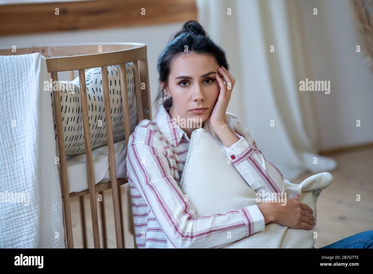 Sad young woman hugging pillow, leaning on cot with propped head Stock ...
