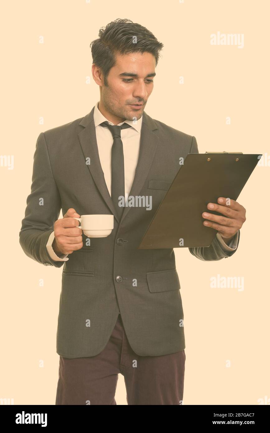 Young handsome Persian businessman holding coffee cup while reading ...