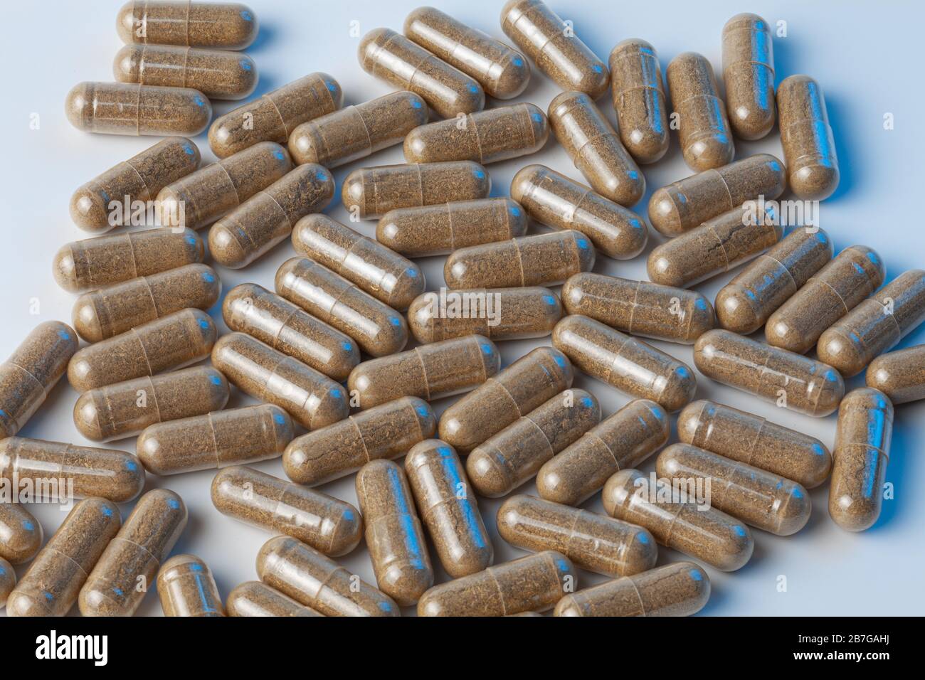 brown capsules pills on a white background with blue lights Stock Photo ...